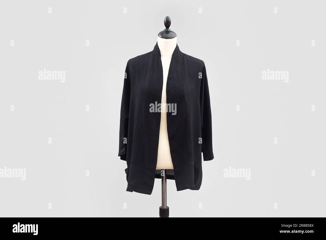 A black, simple jacket without buttons displayed on a headless ...
