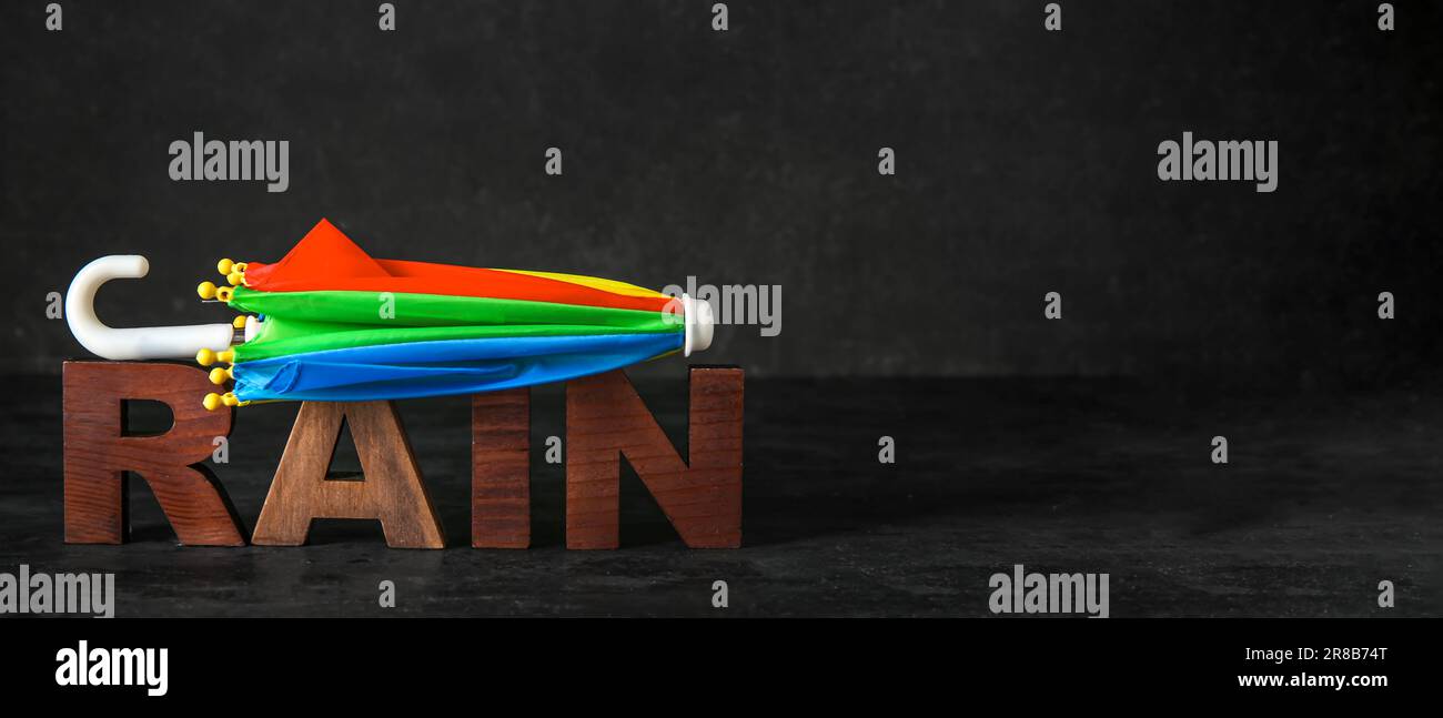 Mini umbrella and word RAIN on black background with space for text ...