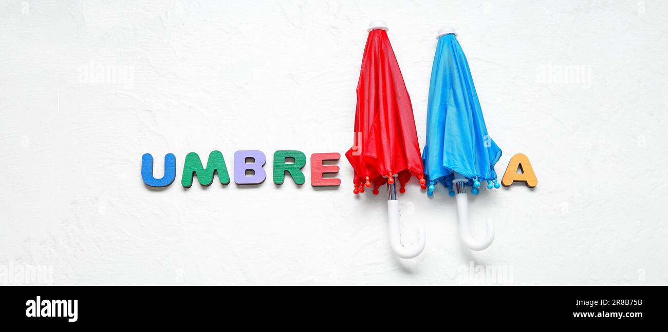 Composition with mini parasols and word UMBRELLA on white background ...
