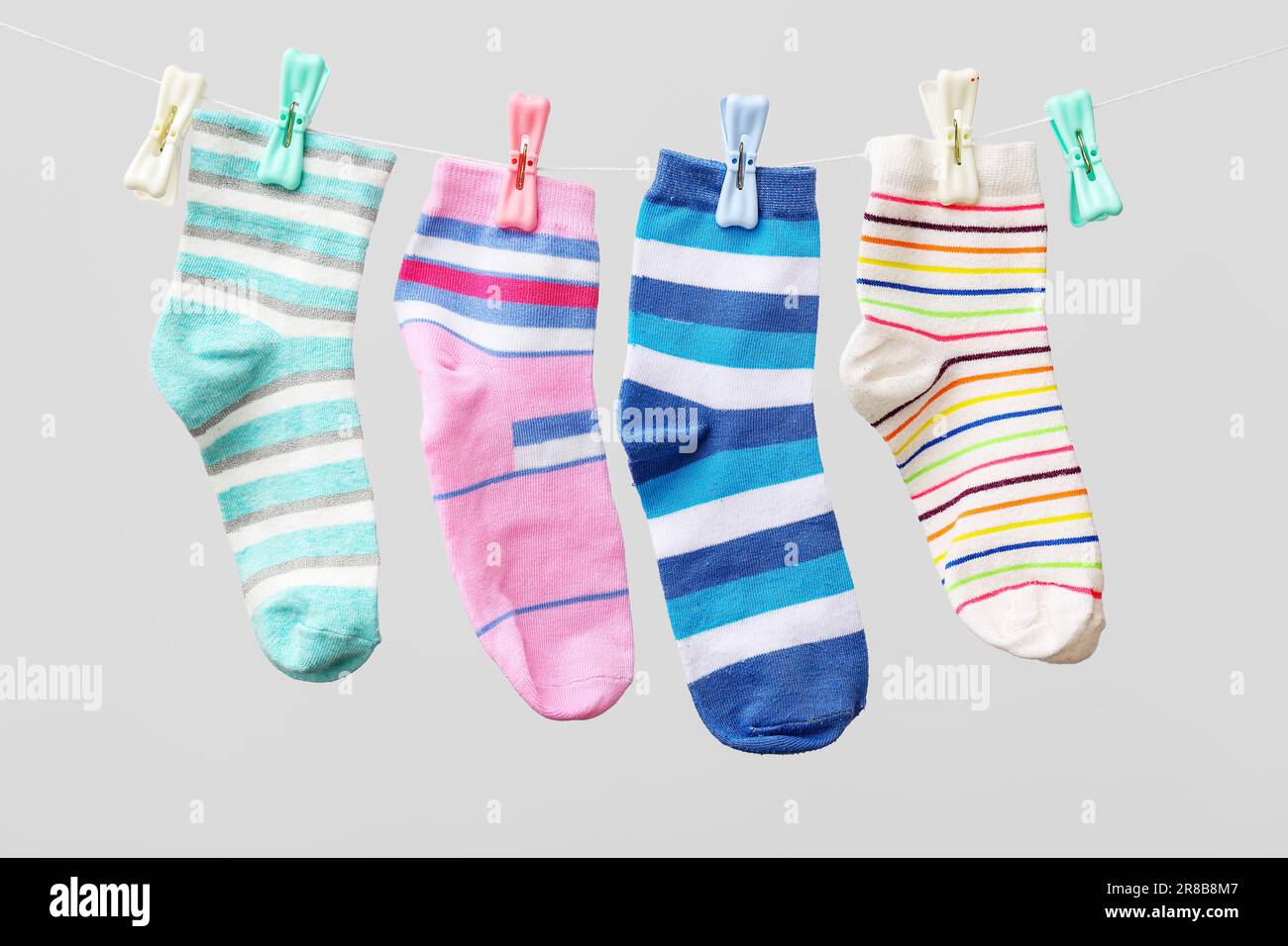 Different socks hanging on rope against light background Stock Photo ...