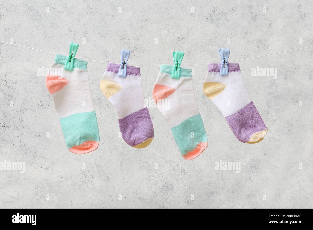 Cotton socks hanging on rope against light background Stock Photo - Alamy