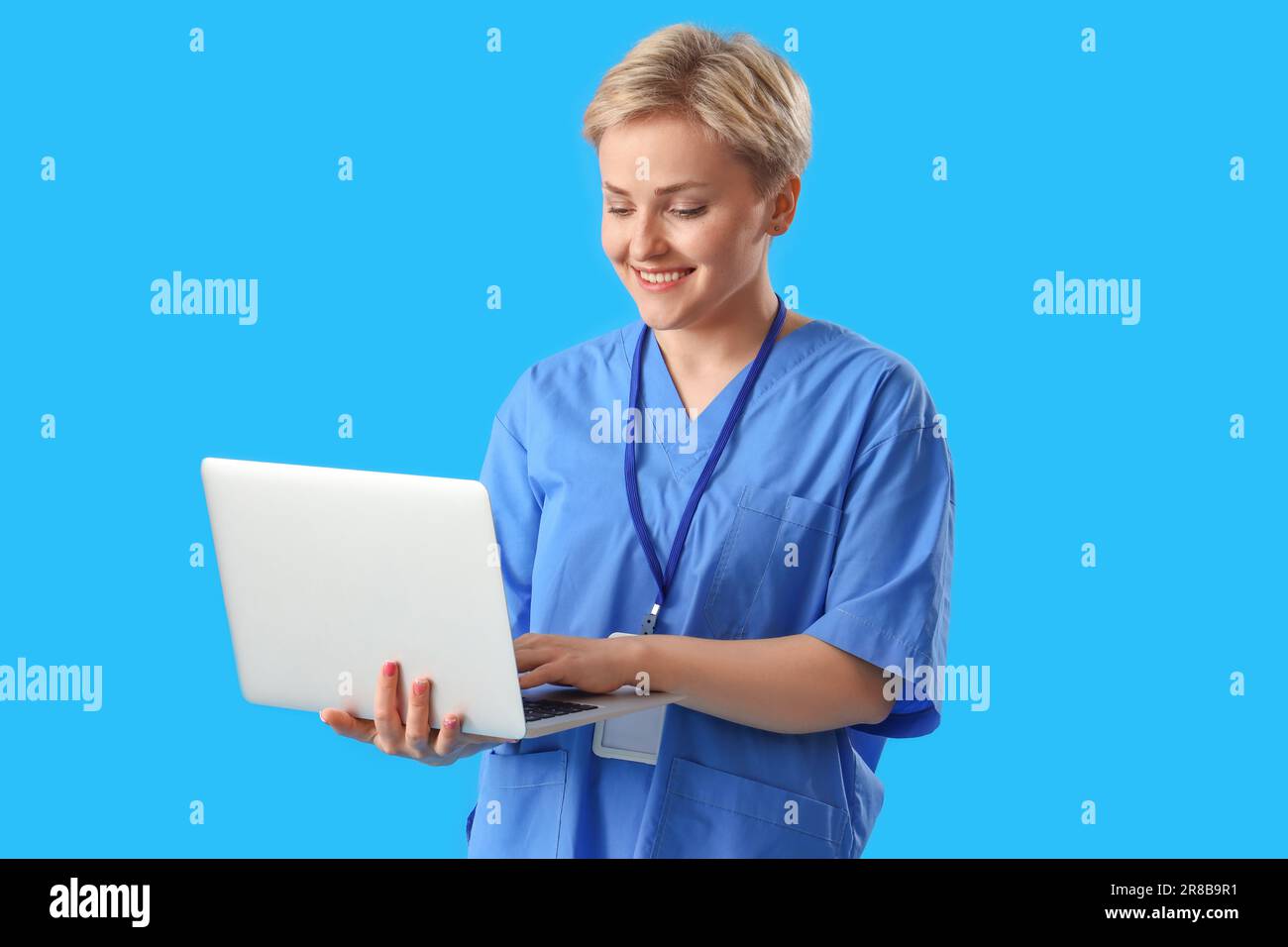 Female medical intern using laptop on blue background Stock Photo - Alamy