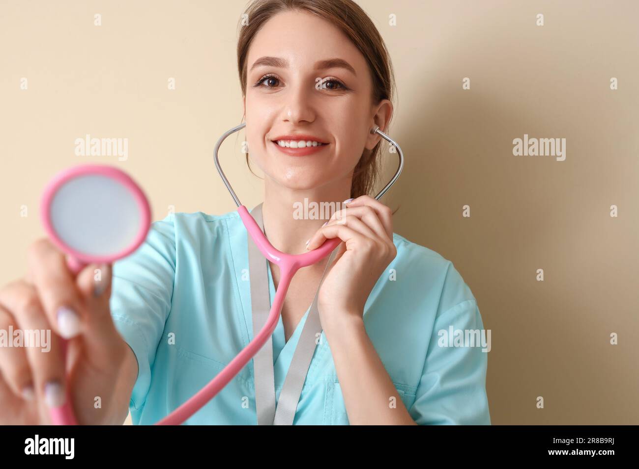 Female medical intern with stethoscope on beige background, closeup ...