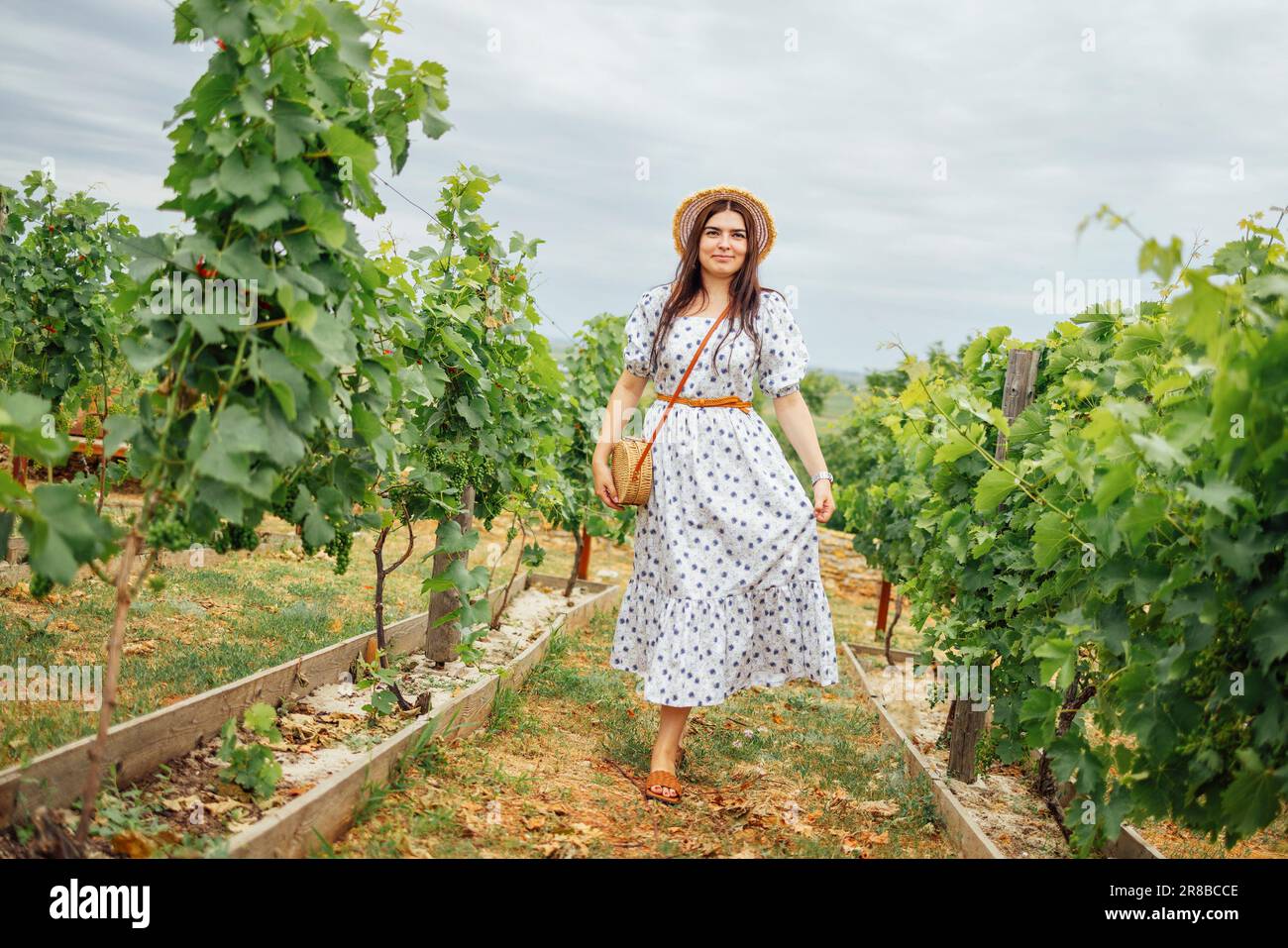 Young enchanting woman in summer sundress with floral pattern, hat and ...