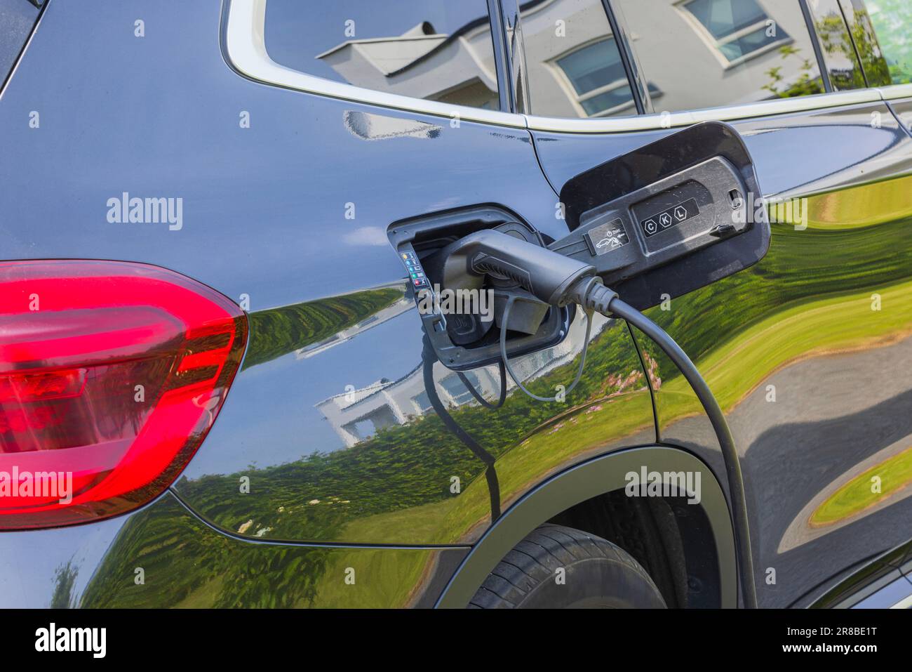 View of connected charging cable to black car from an electric vehicle ...