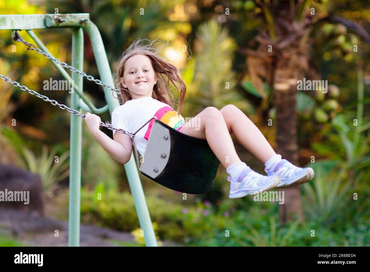 Child swinging on playground on sunny summer day in a park. Kids swing ...