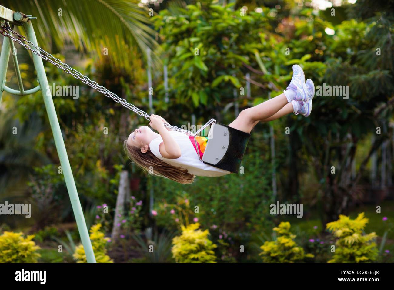 Child swinging on playground on sunny summer day in a park. Kids swing ...