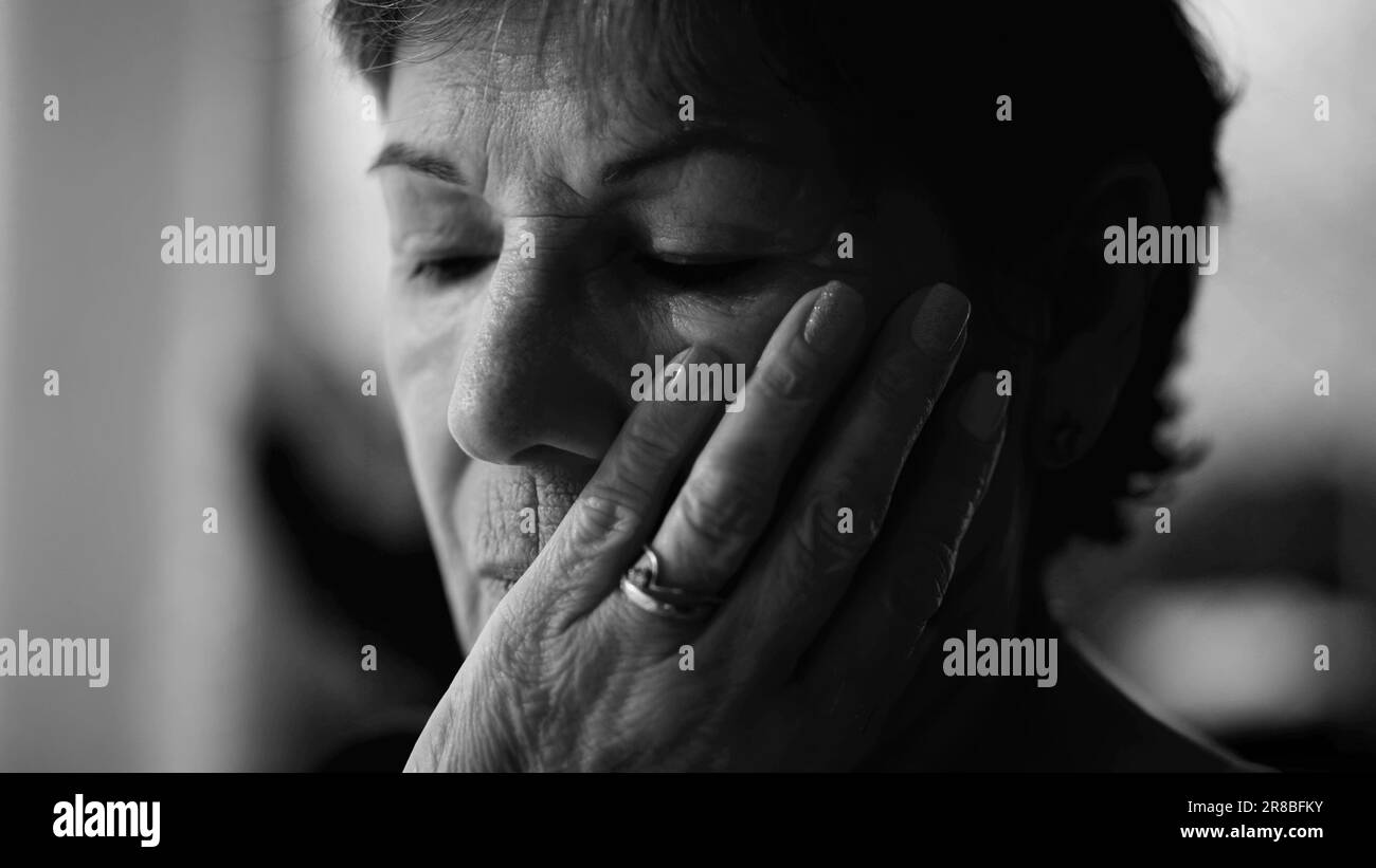Preoccupied senior woman feeling worry and loneliness in monochrome ...