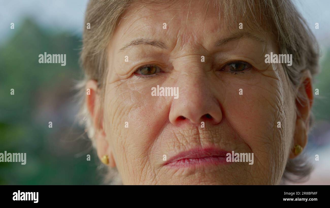 Portrait of a serious older woman close-up face looking at camera ...