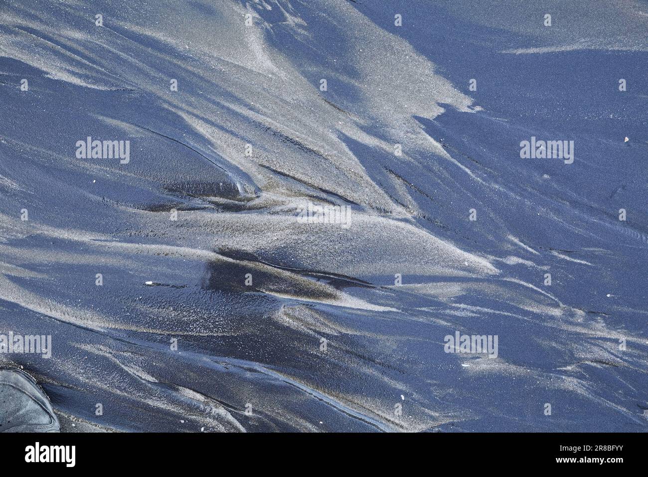 Wet black sand shapes at a beach Stock Photo - Alamy