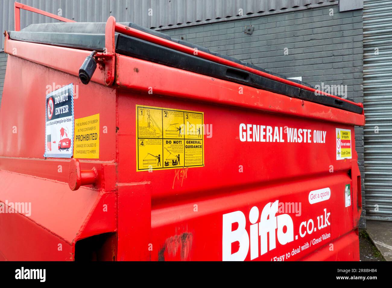 Hazard warning stickers on a red metal recycling skip Stock Photo - Alamy