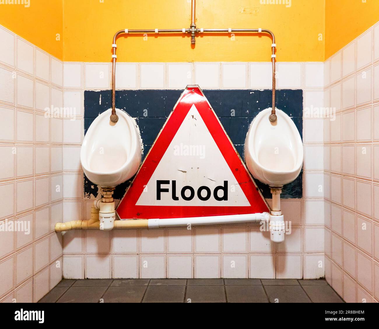 Urinals in a gents toilet with an old triangular flood warning traffic ...