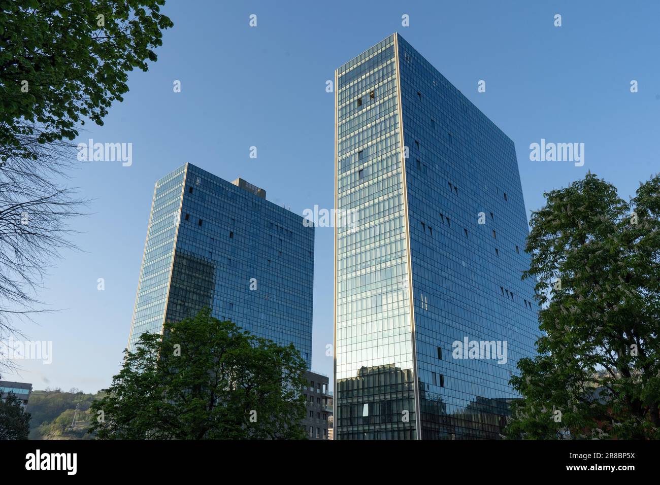 Low angle image of two twin rectangular buildings with glass enclosures ...