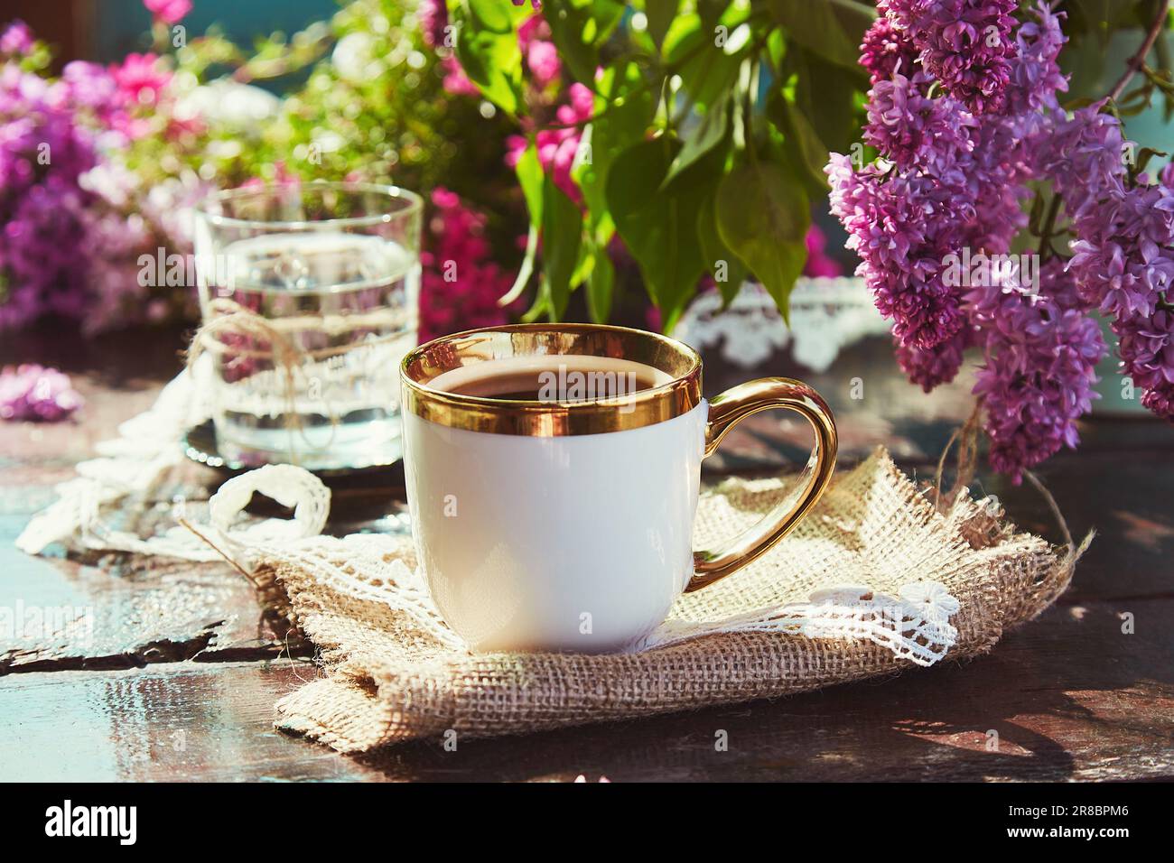 Coffee break with cup of coffee among lilac flowers. Floral creative ...