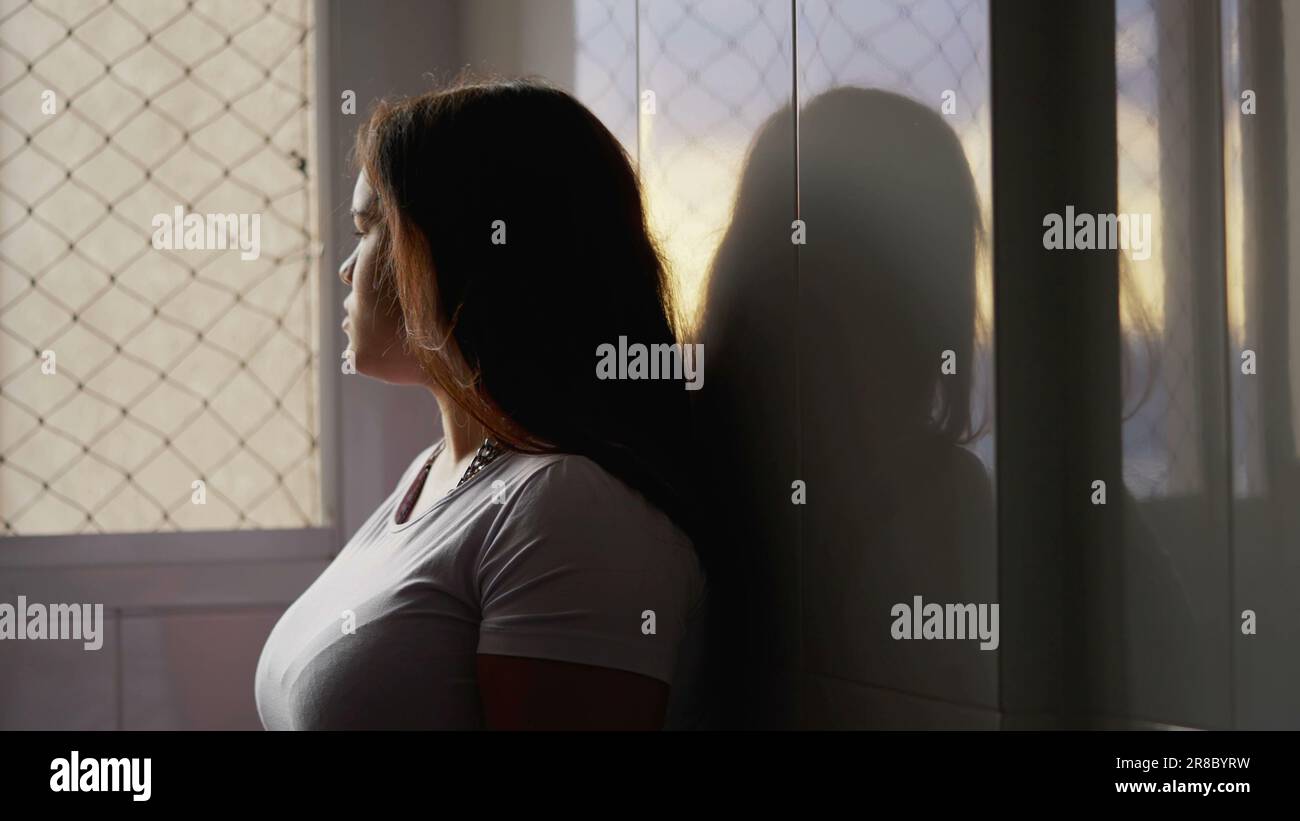 Contemplative Young Female Leaning Against Wall, Peering Out Window ...