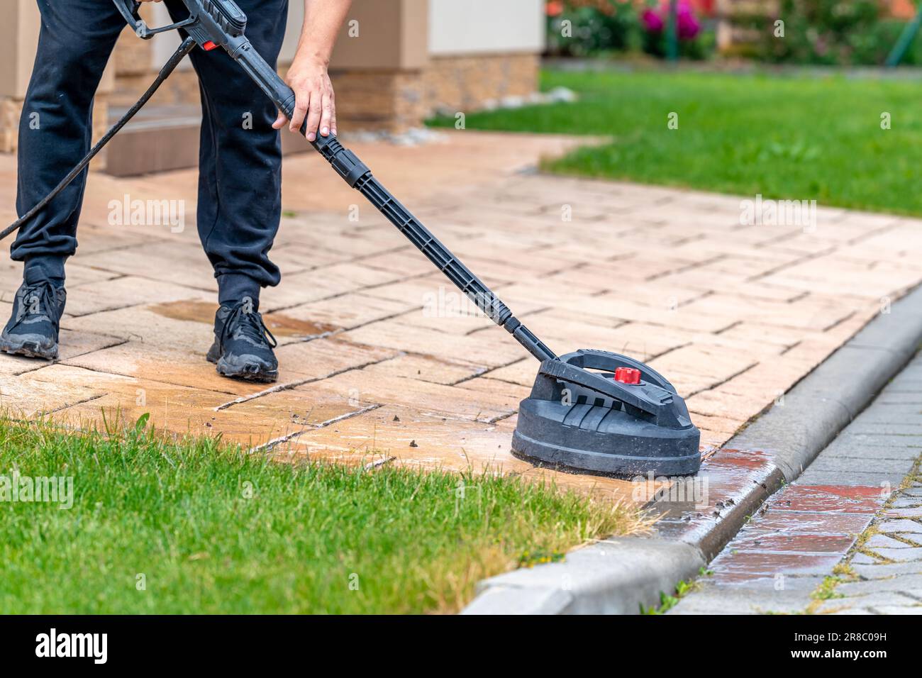 machine cleaning concrete pavement in front of the house with a brush ...