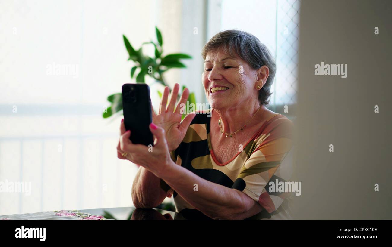 Candid Senior Woman waving hello and Holding Phone while Engaging in ...