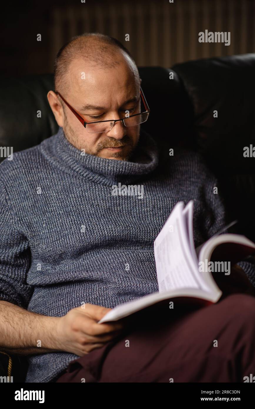 A man with glasses is reading a book. Middle-aged man of ordinary ...