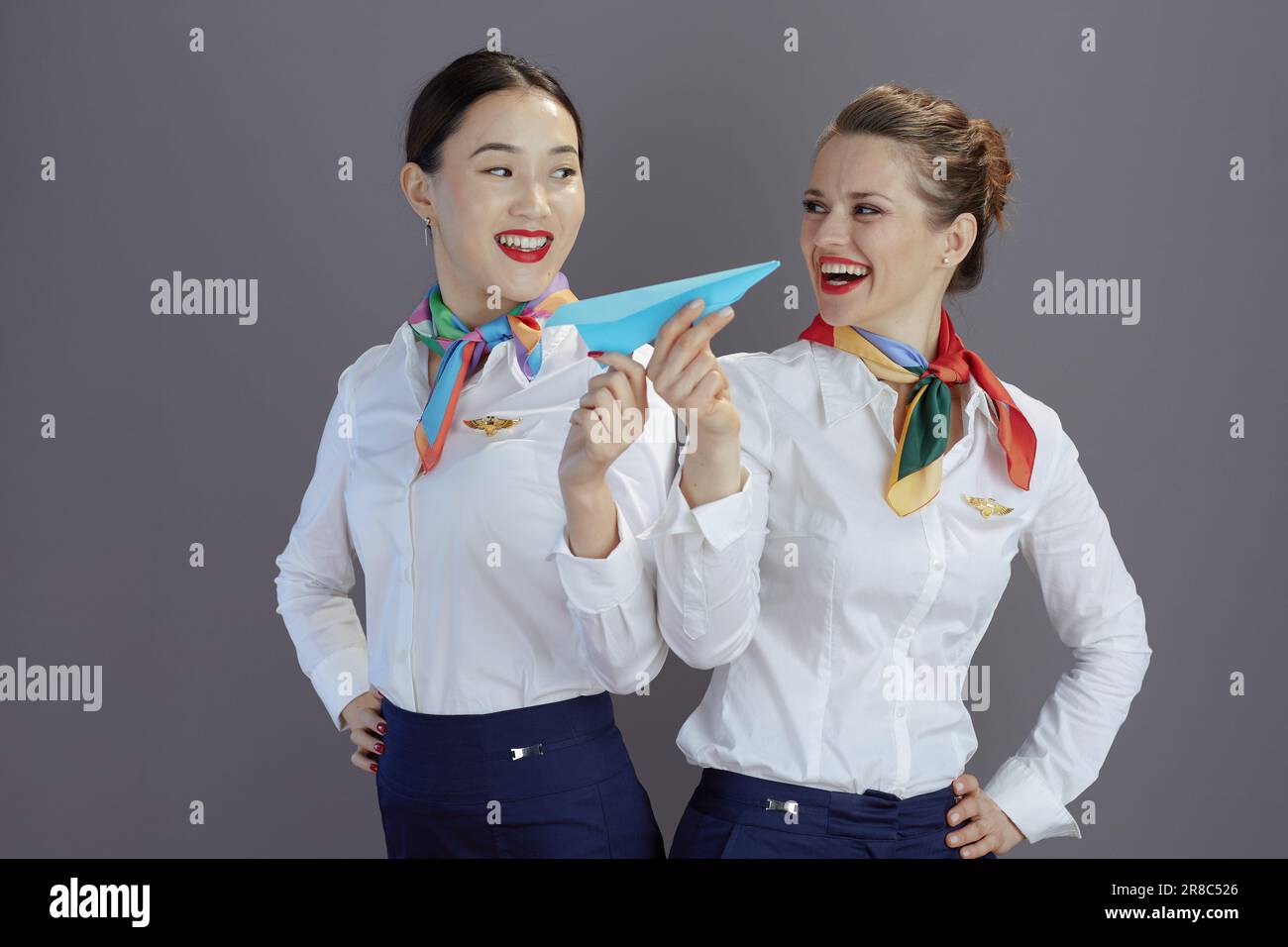 smiling elegant female air hostesses in blue skirt, white shirt and ...