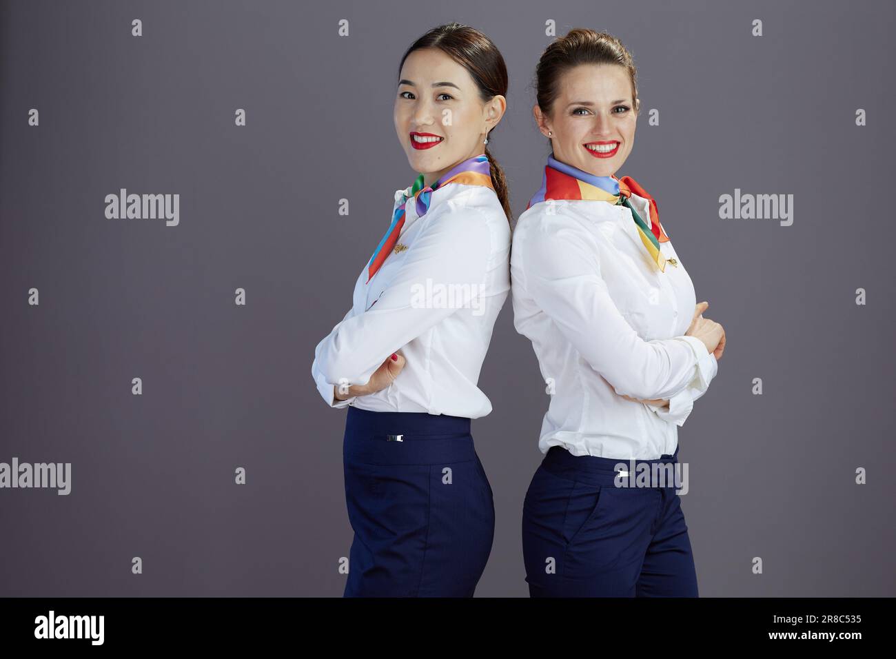 Portrait of happy modern female air hostesses in blue skirt, white ...