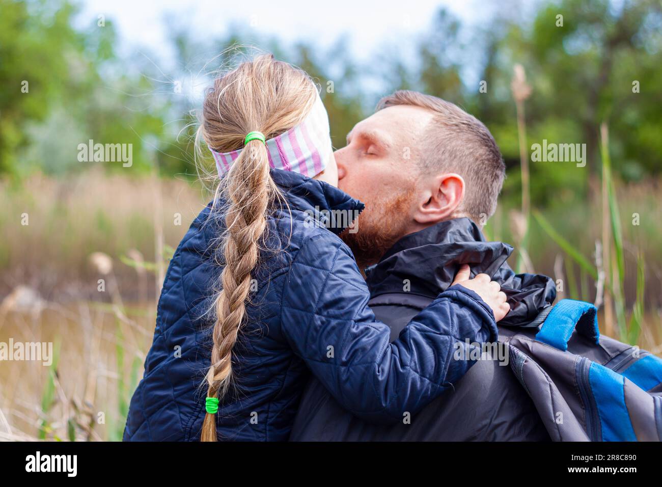 Father and daughter hugging sitting by the lake with nature lanscape ...
