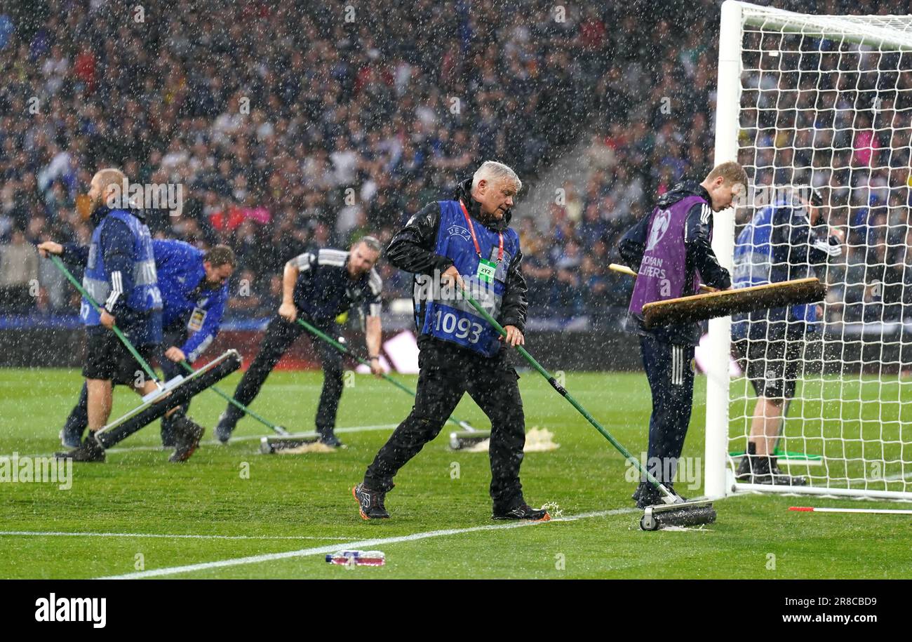 Ground staff sweep water off the pitch as play is suspended during the ...