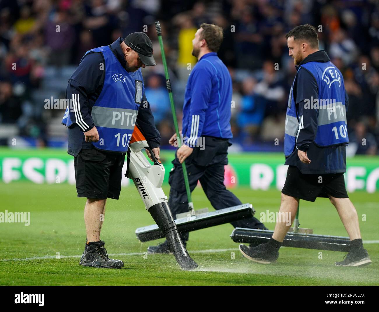 Ground staff clear water off the pitch while play is suspended during ...