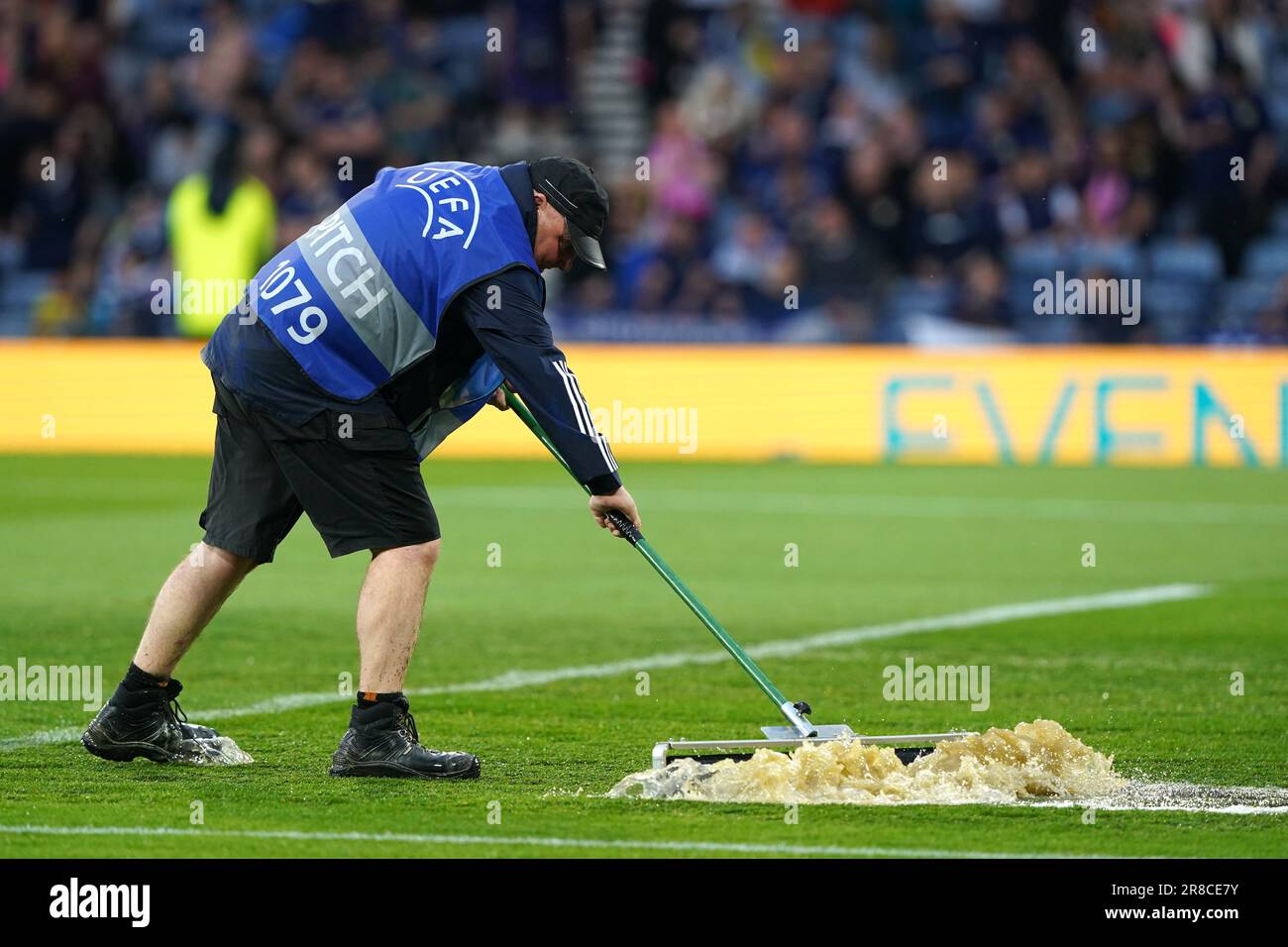 Ground staff sweep water off the pitch while play is suspended during ...