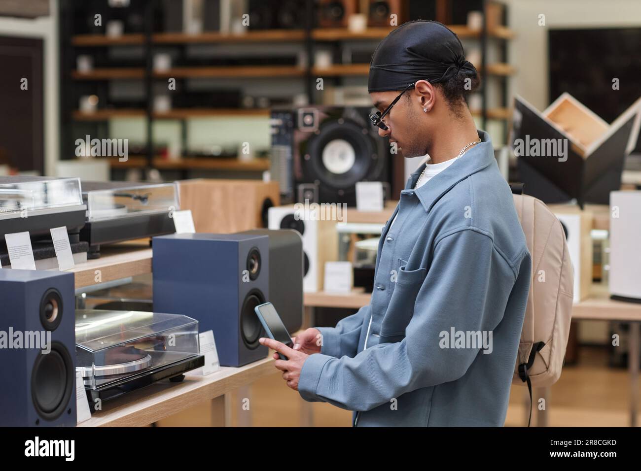 Side view portrait of young black man looking at vinyl record player in ...