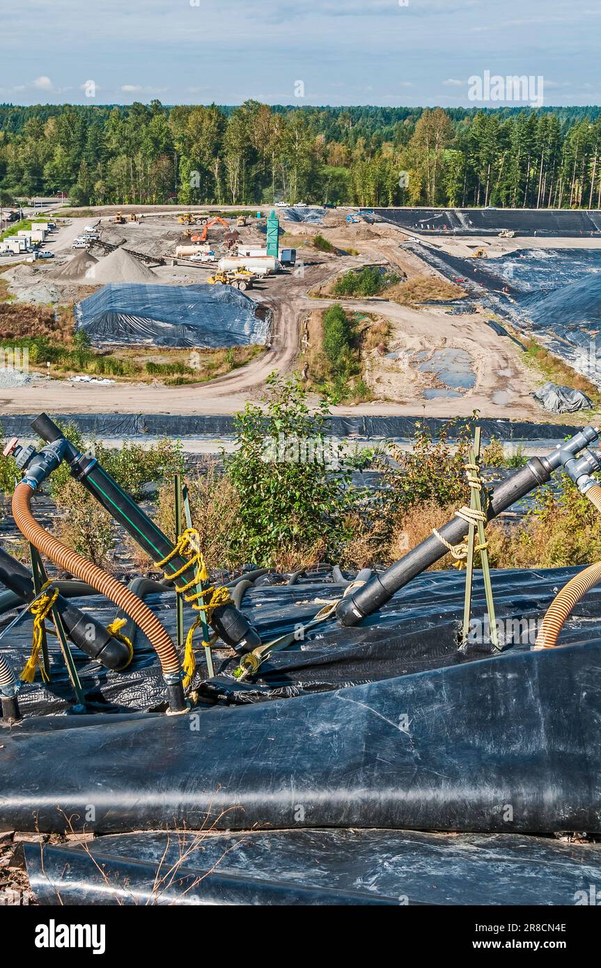 Methane gas well heads poke out of a geomembrane overlooking hills and ...