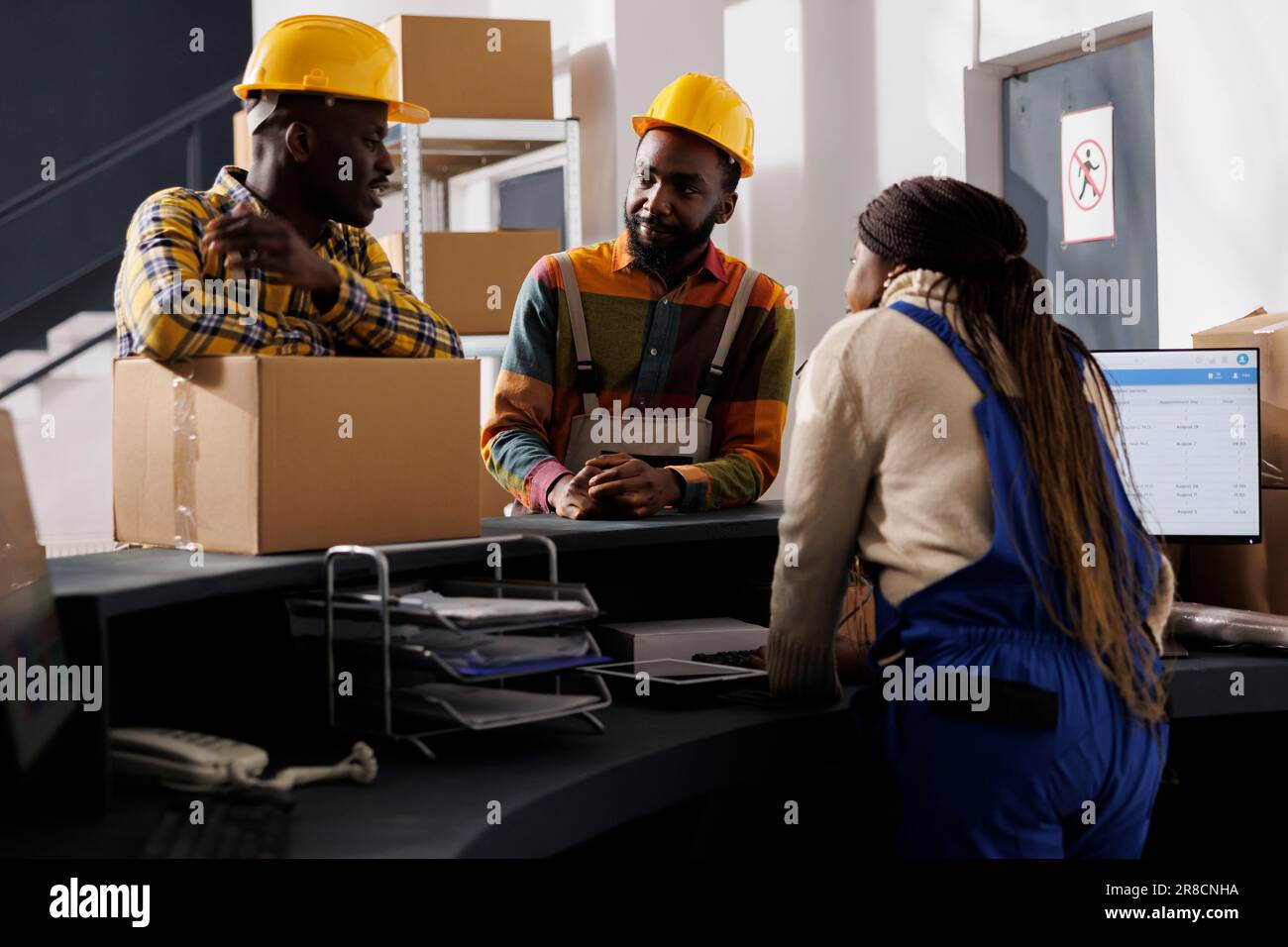 Warehouse workers holding parcel at reception, discussing package ...