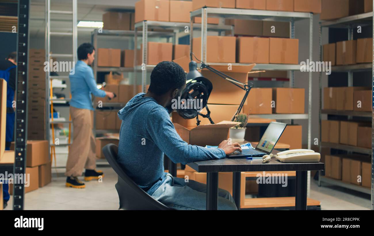 Young office worker checking goods in cardboard packages, looking at ...