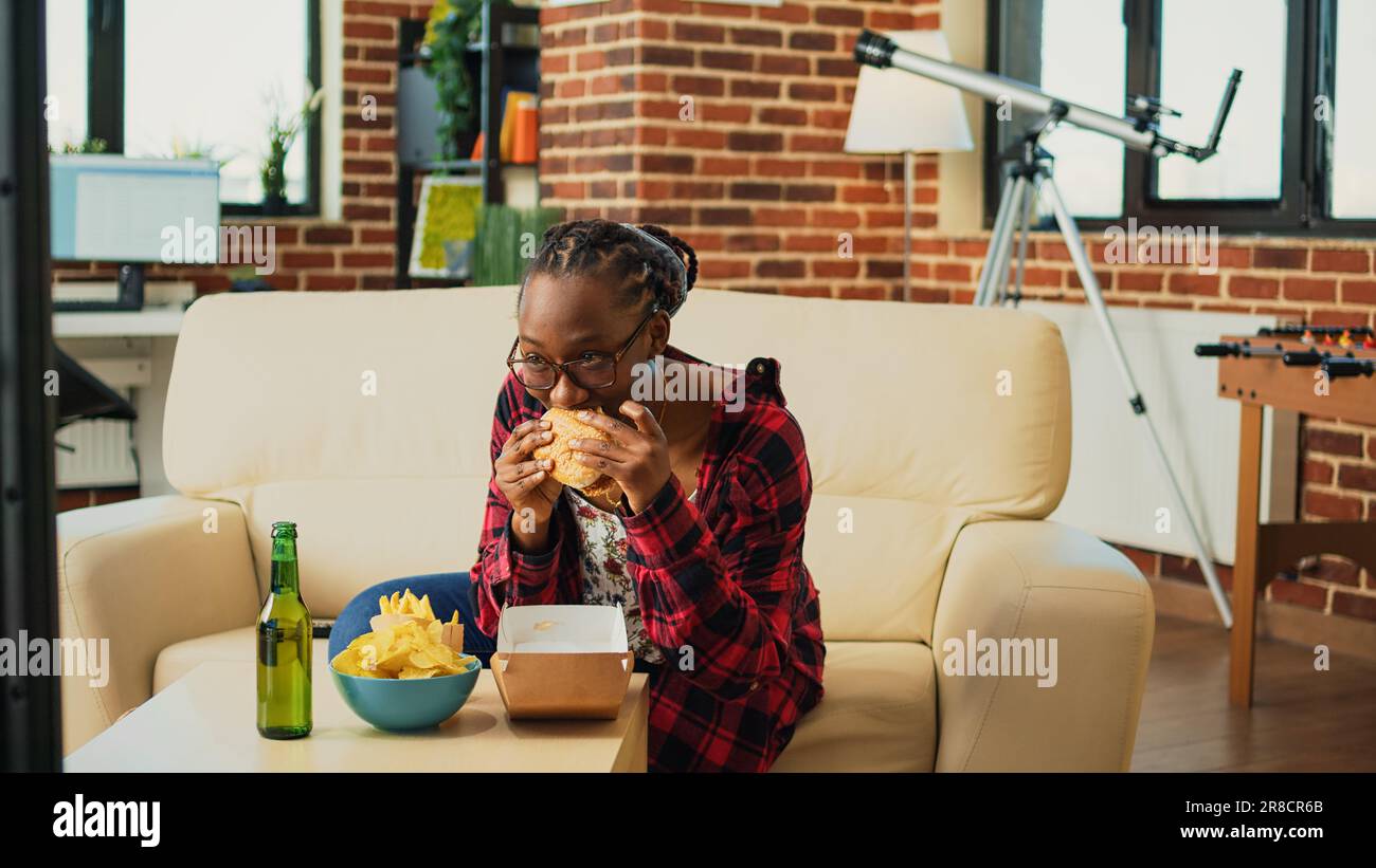 Cheerful person eating hamburger from fast food takeout, enjoying meal ...