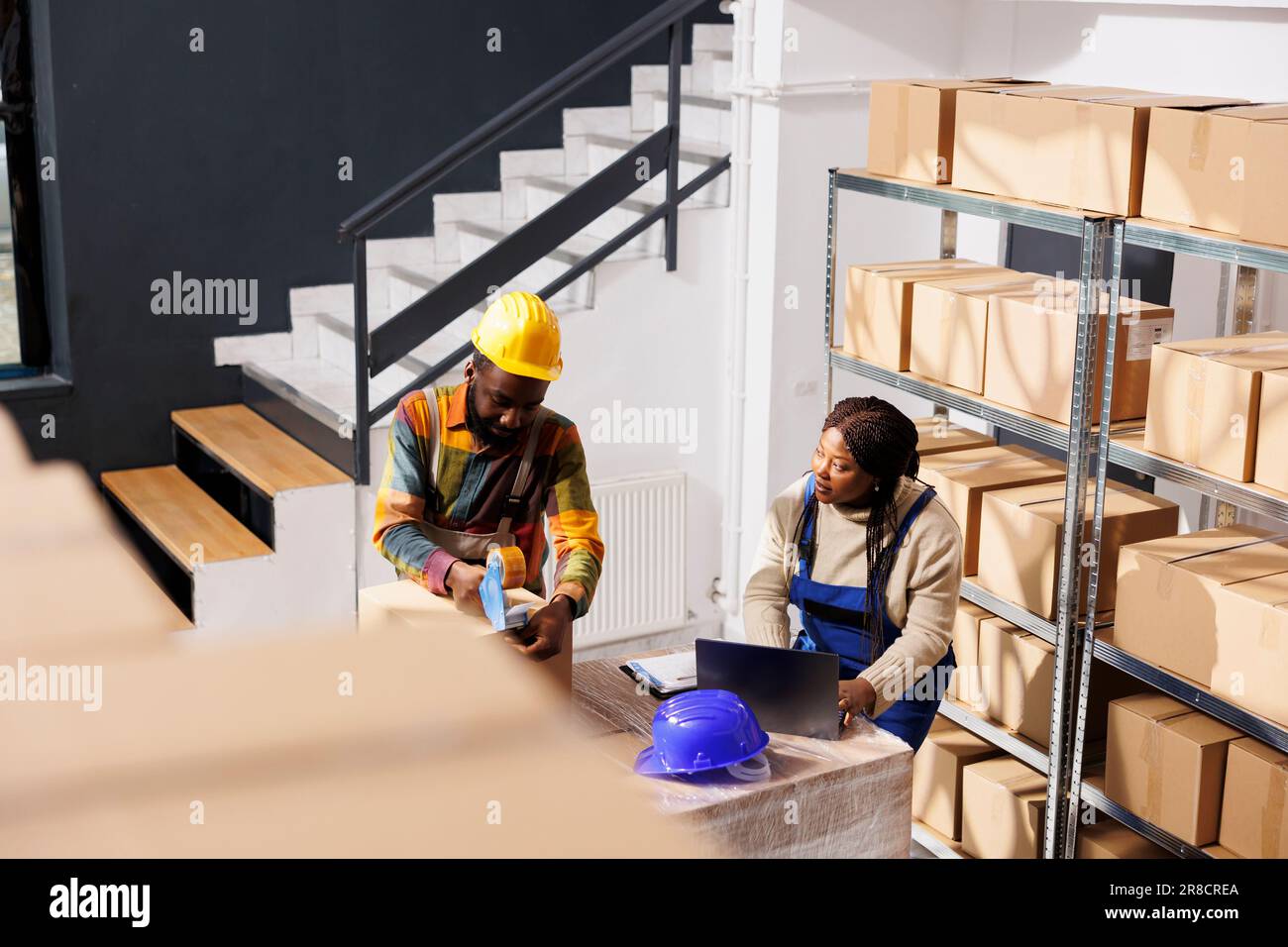 African american warehouse manager monitoring package handler work in ...