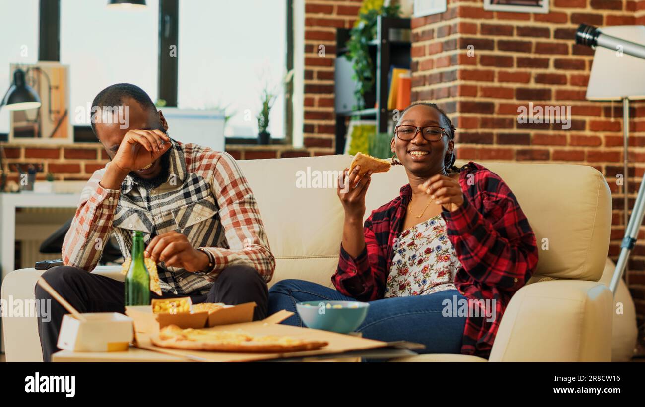 Happy life partners eating pizza and watching film on television ...