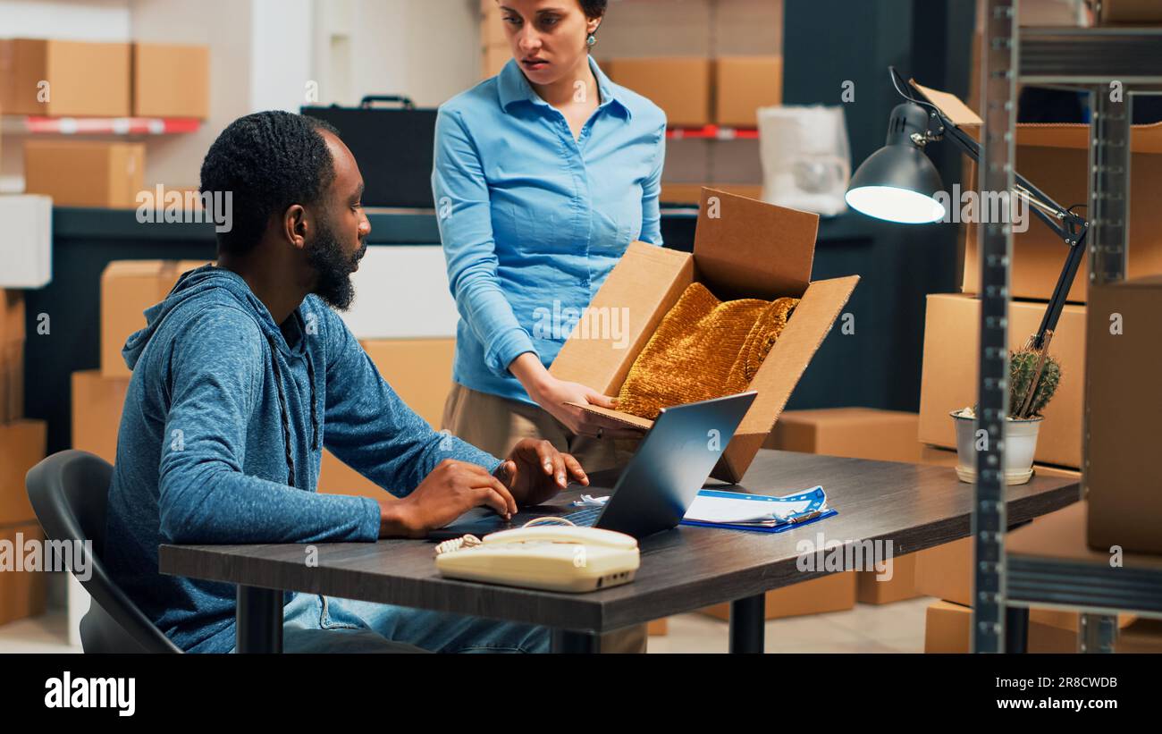 Diverse employees shipping storage products from warehouse, looking at ...