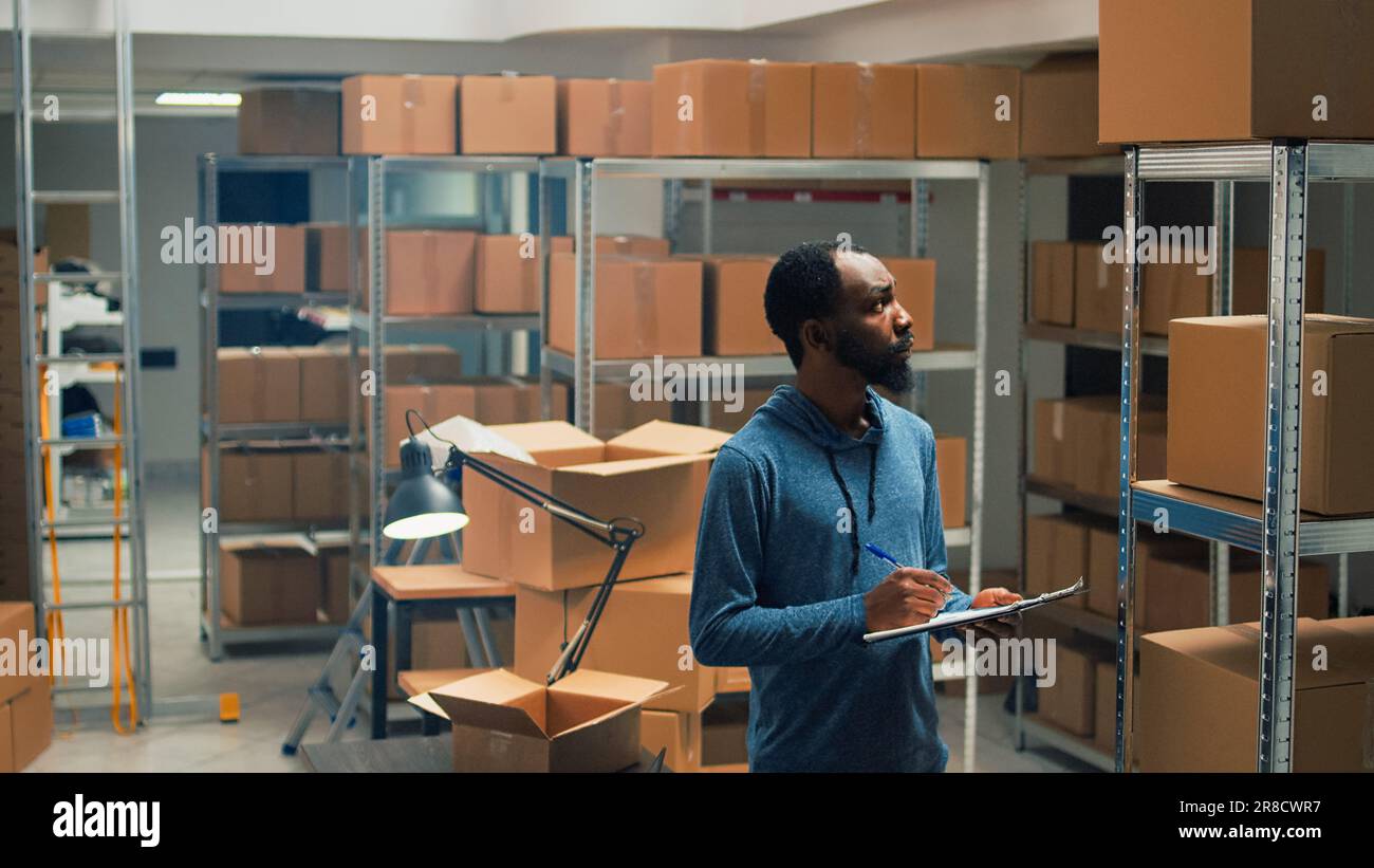 Male entrepreneur taking inventory notes on clipboard files, checking ...