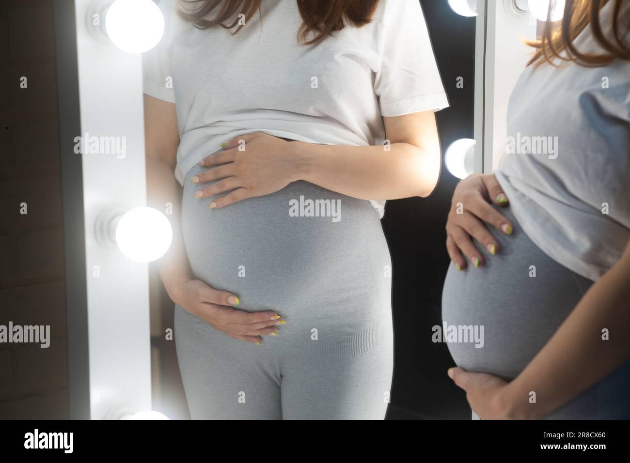 Unrecognizable pregnant woman with big belly in front of mirror ...