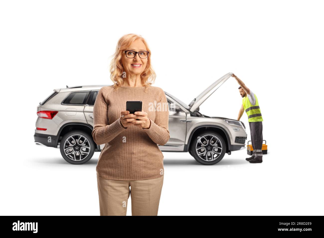 Road assistance worker fixing a car and woman holding a smartphone ...