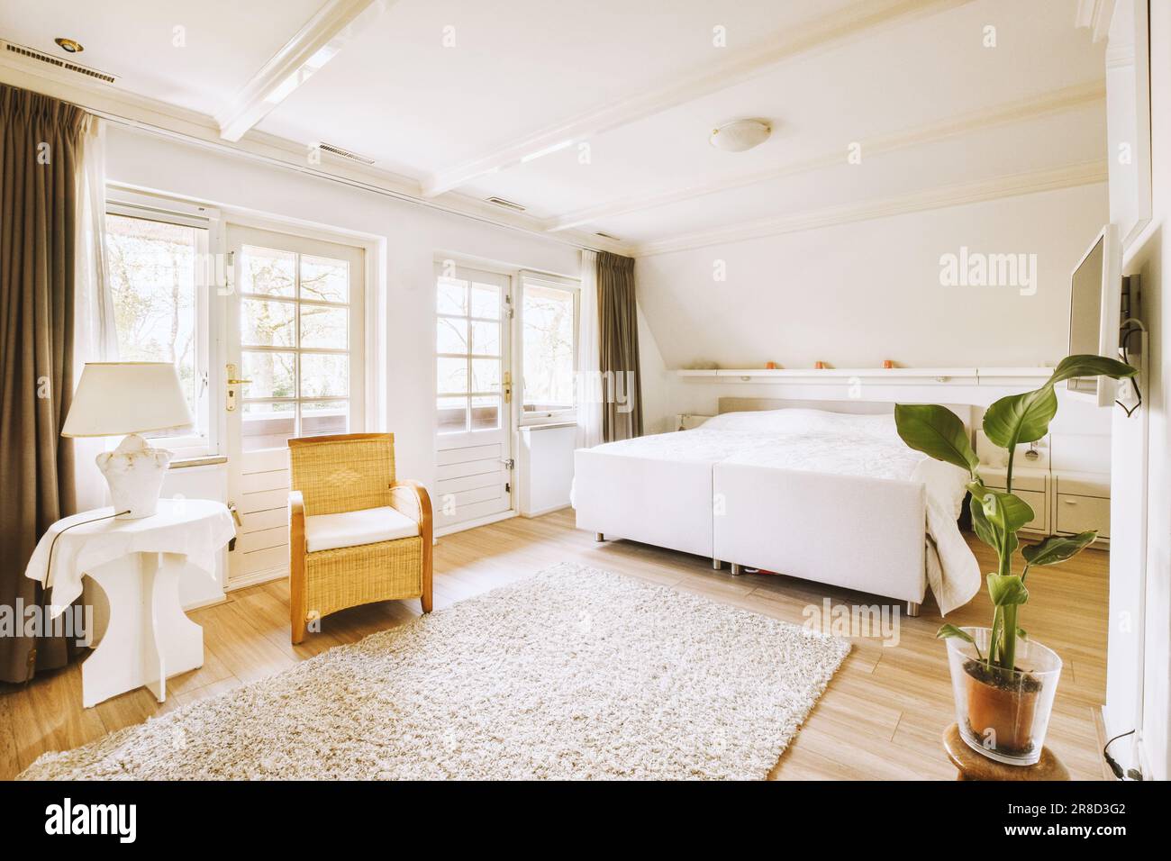 a bedroom with a bed, desk and chair in the fore - windowed room that ...