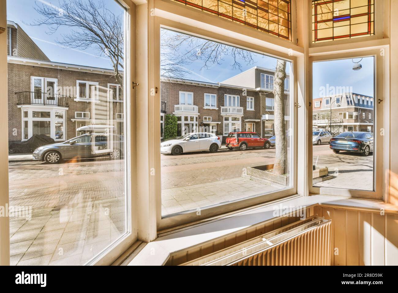 a window with cars parked in the street and buildings on both sides, as ...