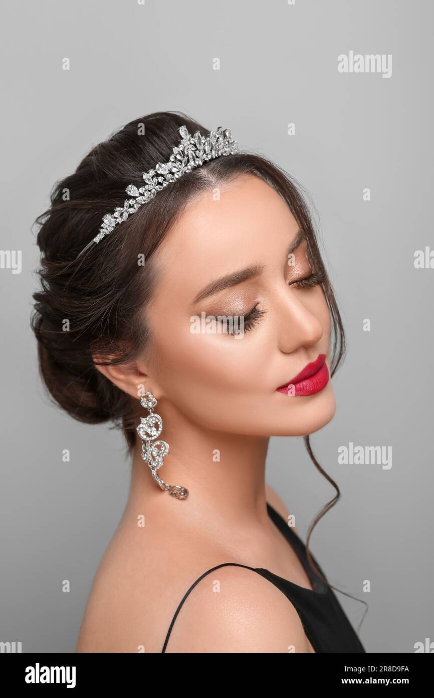 Beautiful young woman wearing luxurious tiara on light grey background ...