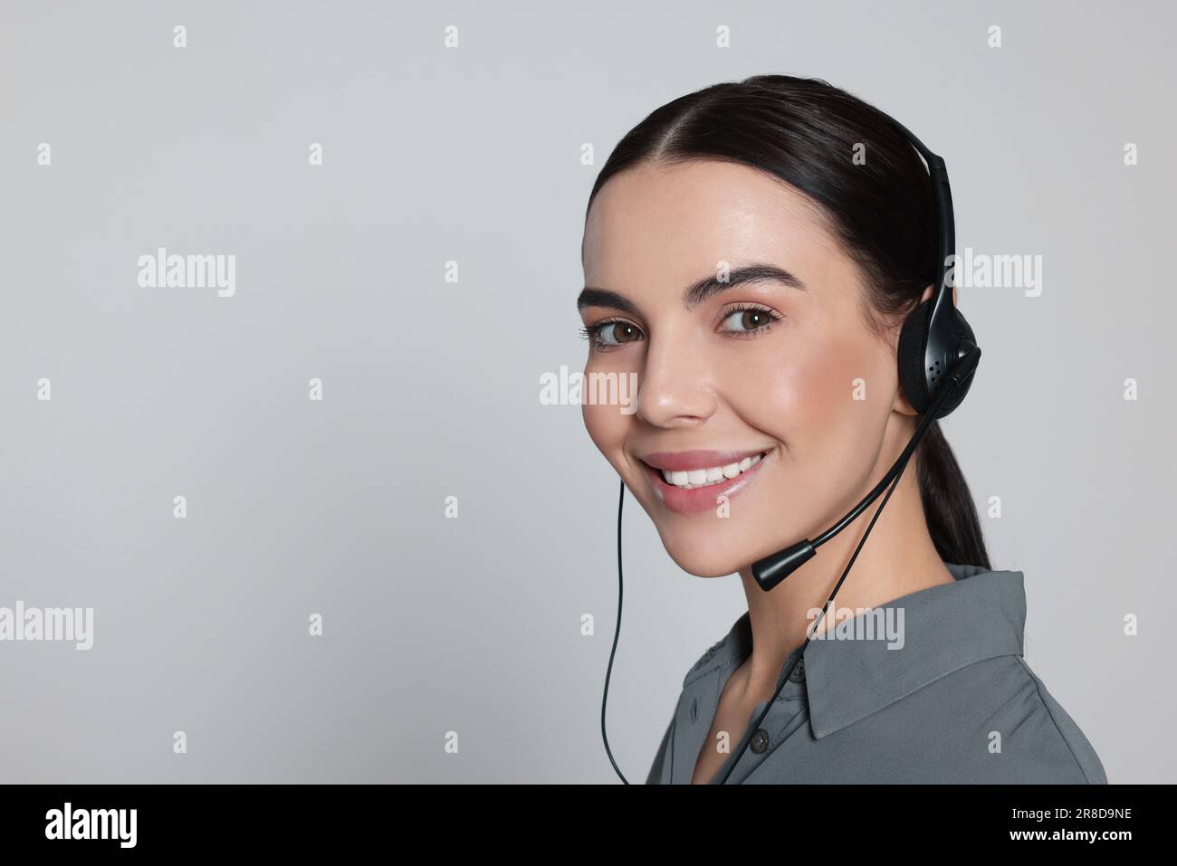 Hotline operator with modern headset on light grey background, space ...