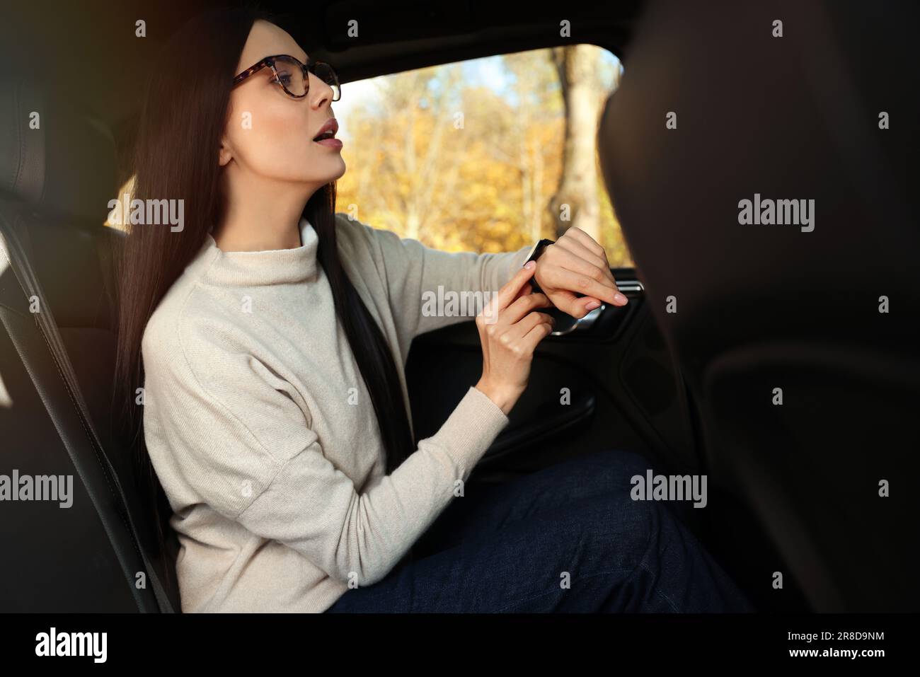 Emotional woman checking time on watch in car. Being late concept Stock ...