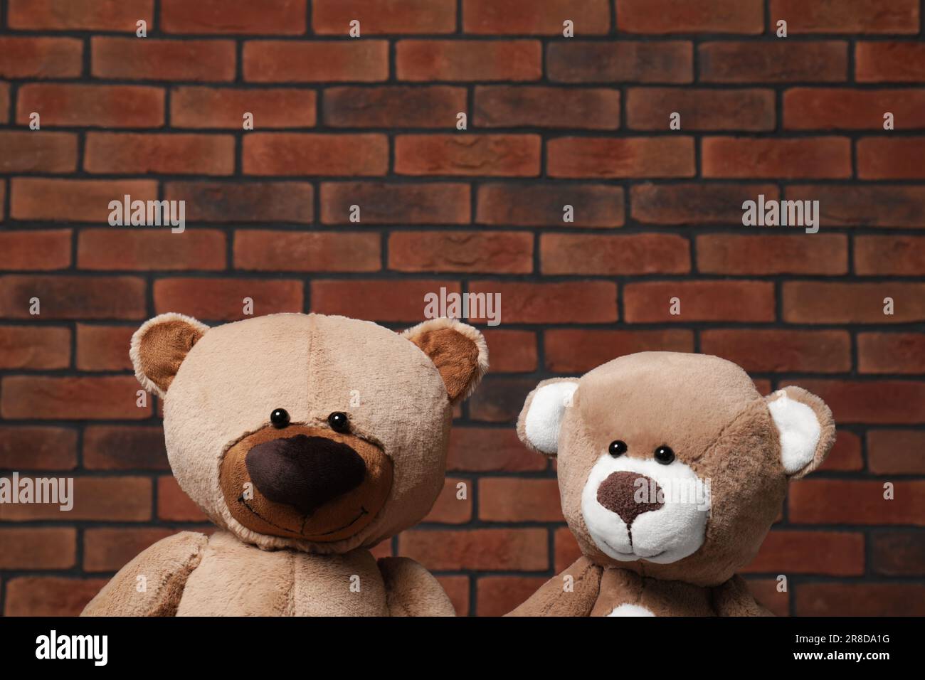 Cute teddy bears against brick wall. Space for text Stock Photo - Alamy