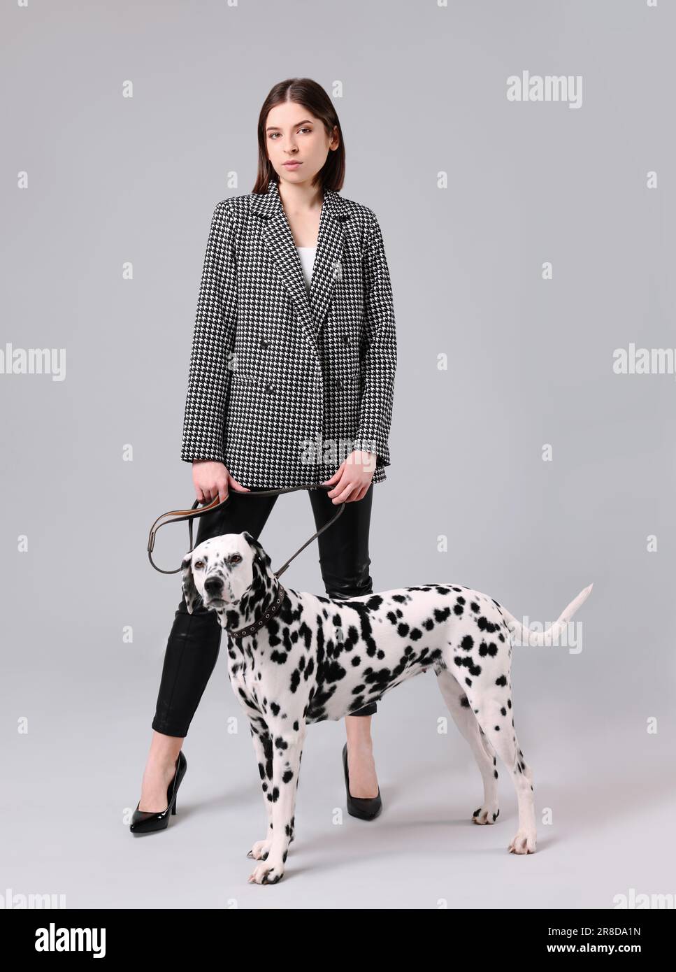 Beautiful young woman with her adorable Dalmatian dog on light grey ...
