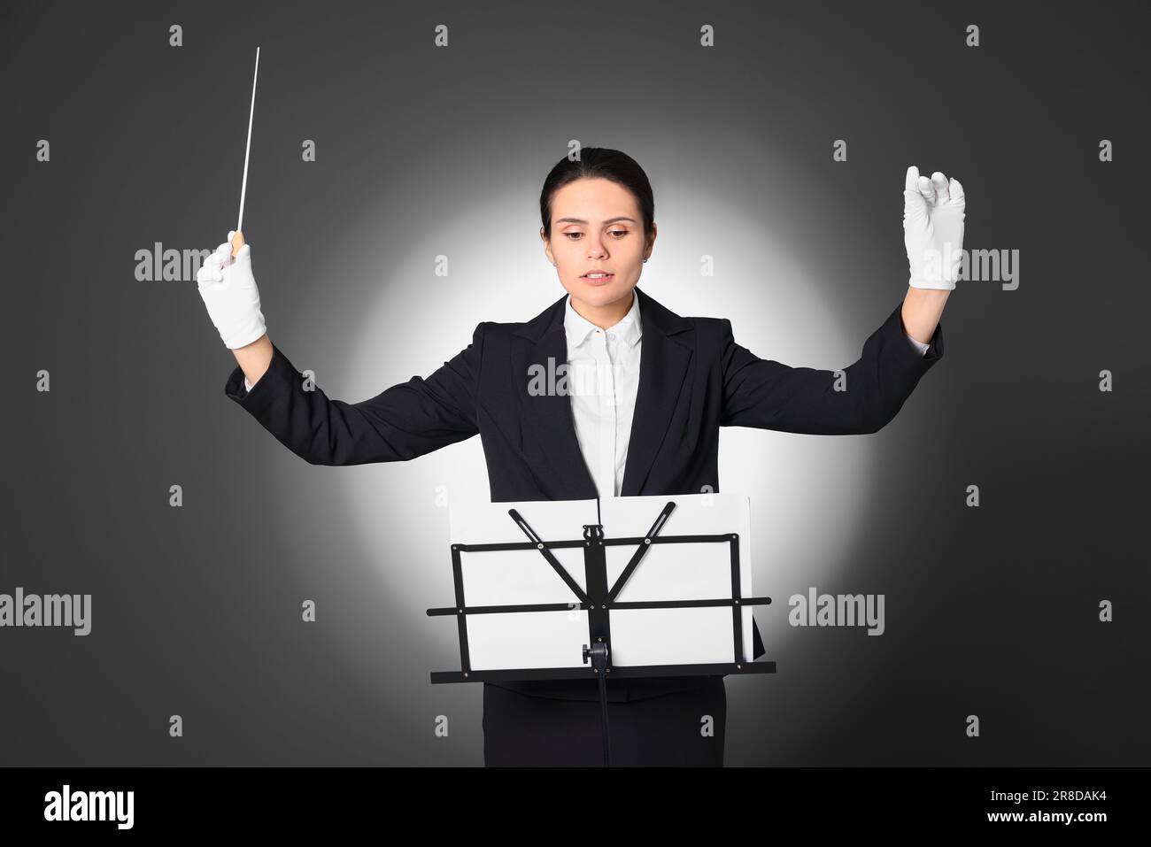 Professional conductor with baton and note stand on grey background ...