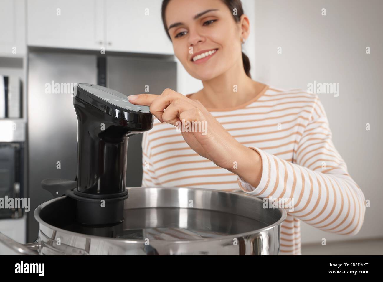 Woman using thermal immersion circulator in kitchen, focus on hand ...