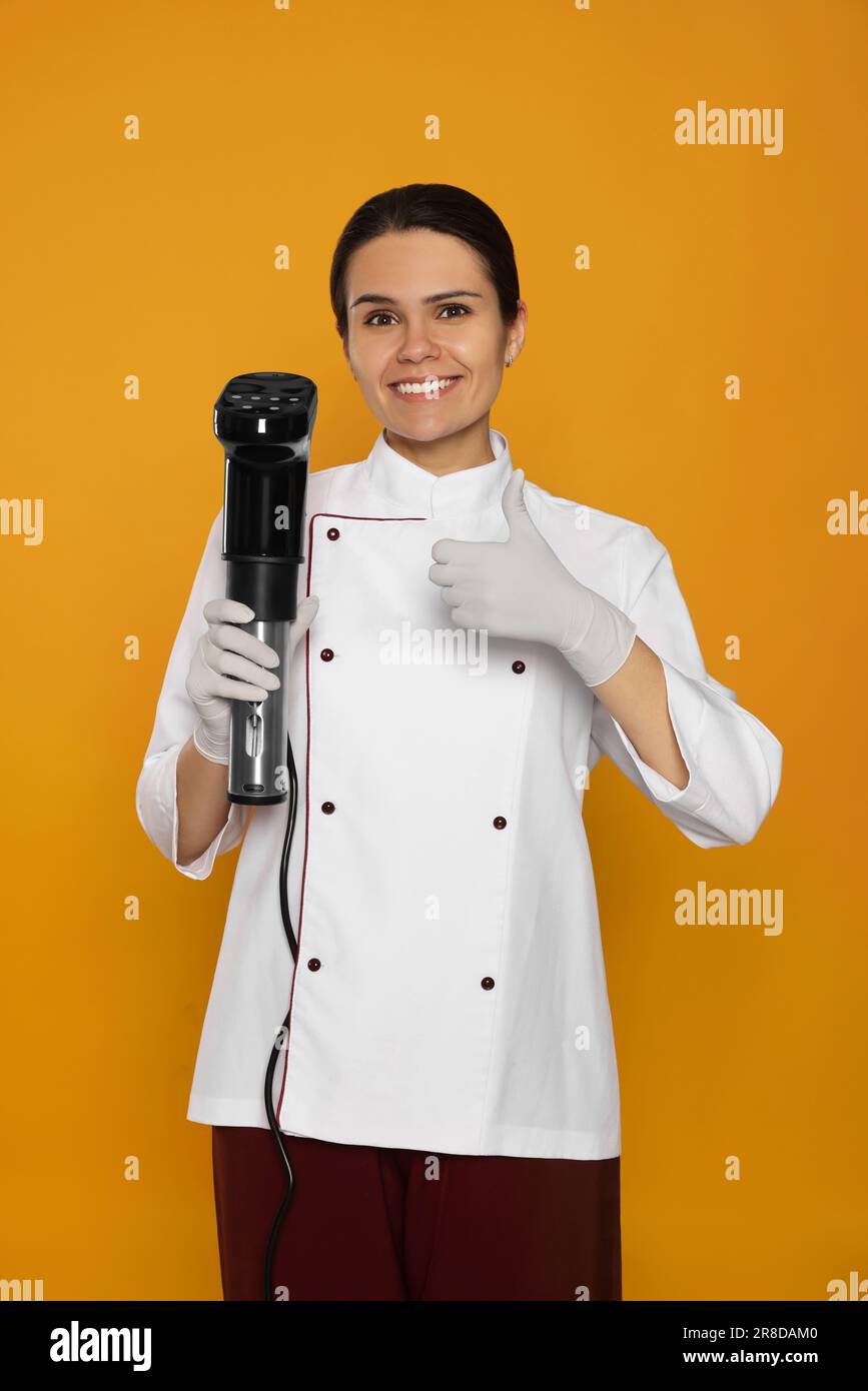 Chef holding sous vide cooker on orange background Stock Photo - Alamy