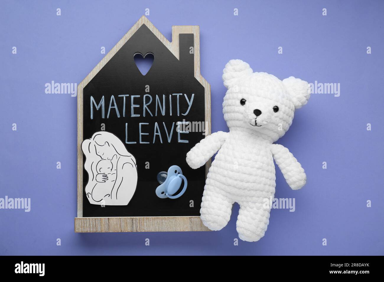 Maternity leave concept. Wooden house figure, baby pacifier, toy bear ...